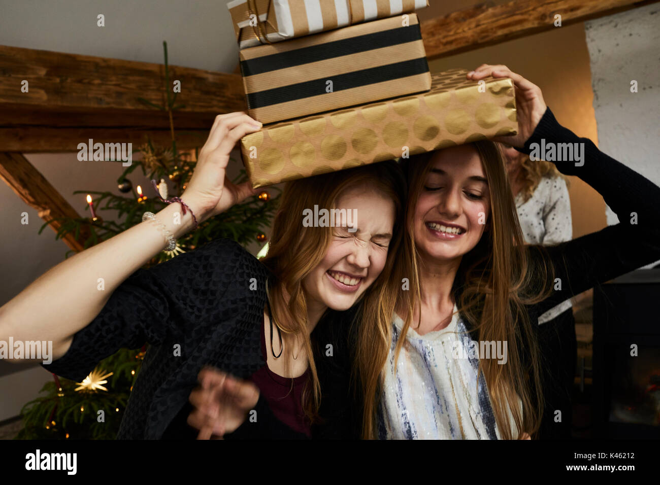 Two girls with presents in front of christmas tree hi-res stock ...
