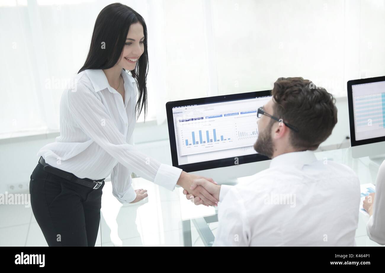 employees greet each other with a handshake near the desk Stock Photo ...