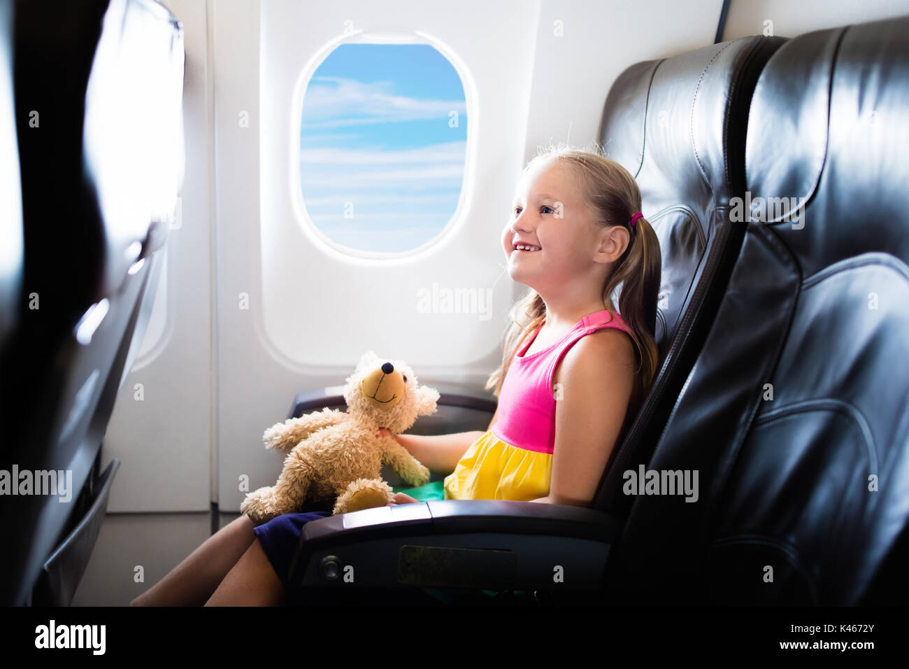 Child in airplane. Kid in air plane sitting in window seat. Flight ...