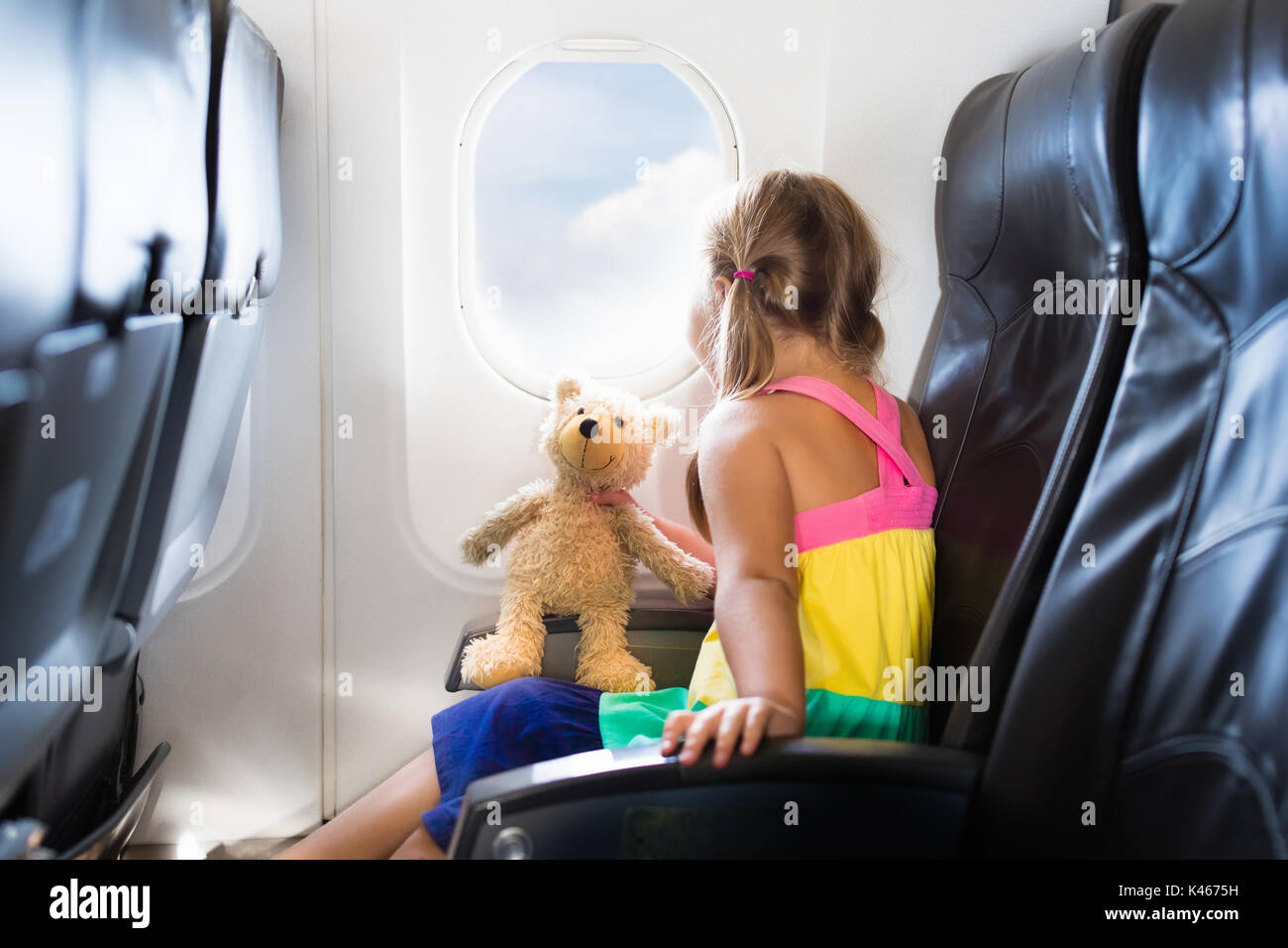 Child in airplane. Kid in air plane sitting in window seat. Flight ...