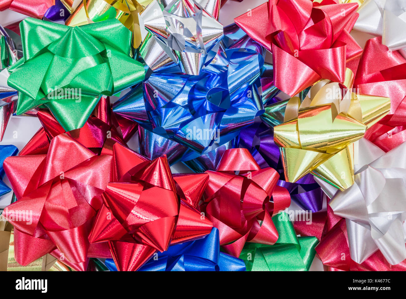 A horizontal photo of a pile of brightly colored and shiny holiday bows ...