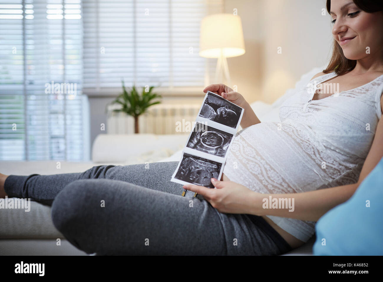Pregnant happy woman sitting on couch and holding ultrasound scan Stock ...