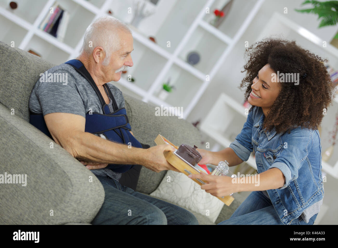 young girl volunteer is giving food to handsome old man Stock Photo - Alamy