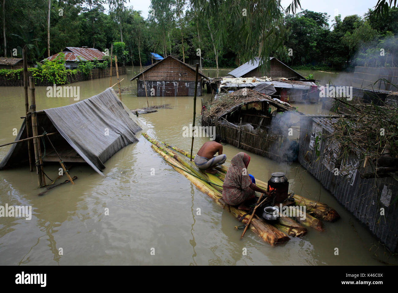 A family cooking on a banana tree raft in front of their flooded home ...