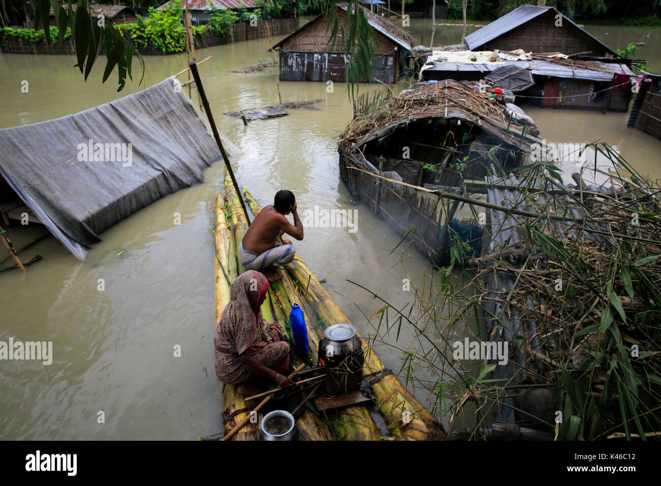 A family cooking on a banana tree raft in front of their flooded home ...
