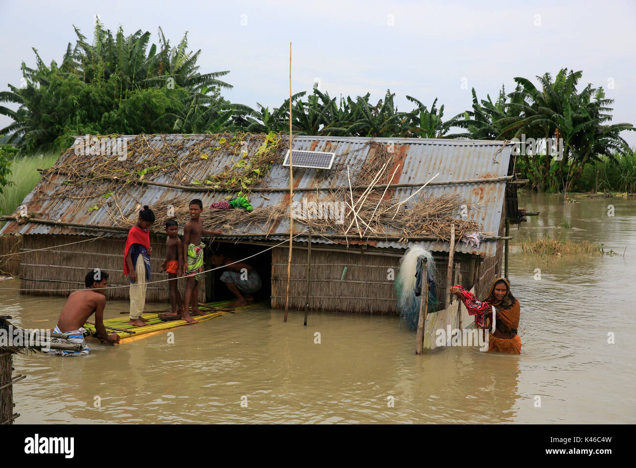 A family cooking on a banana tree raft in front of their flooded home ...