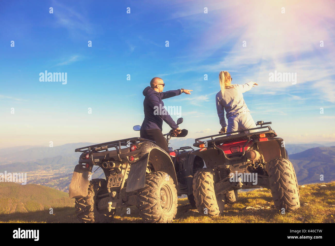 Couple driving off-road with quad bike or ATV Stock Photo - Alamy