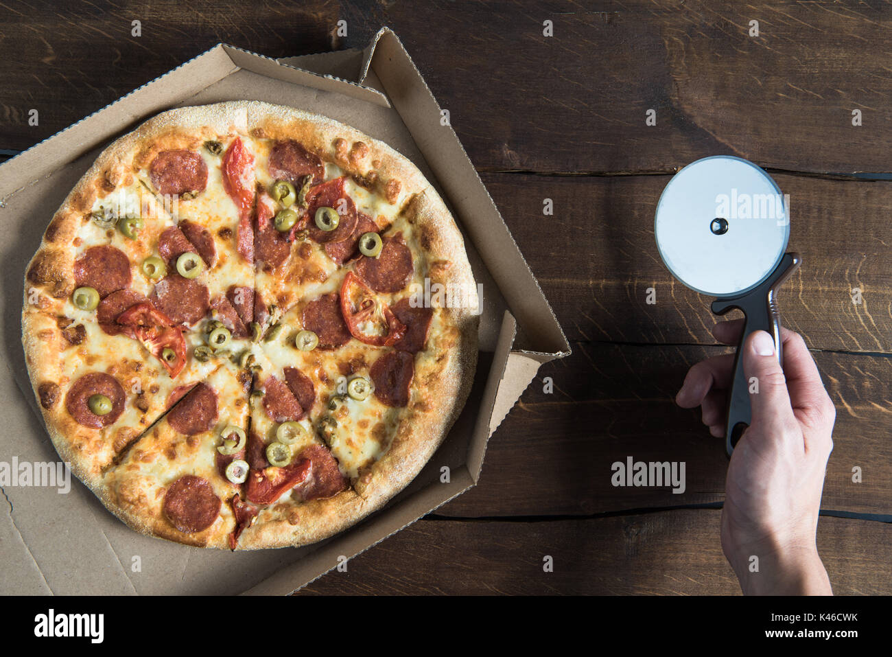 Top view of tasty fresh pizza in cardboard box and pizza cutter in ...