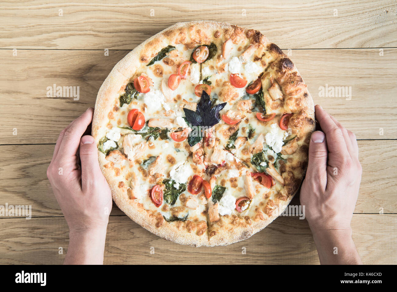 partial view of hands holding italian pizza with basil leaves and ...
