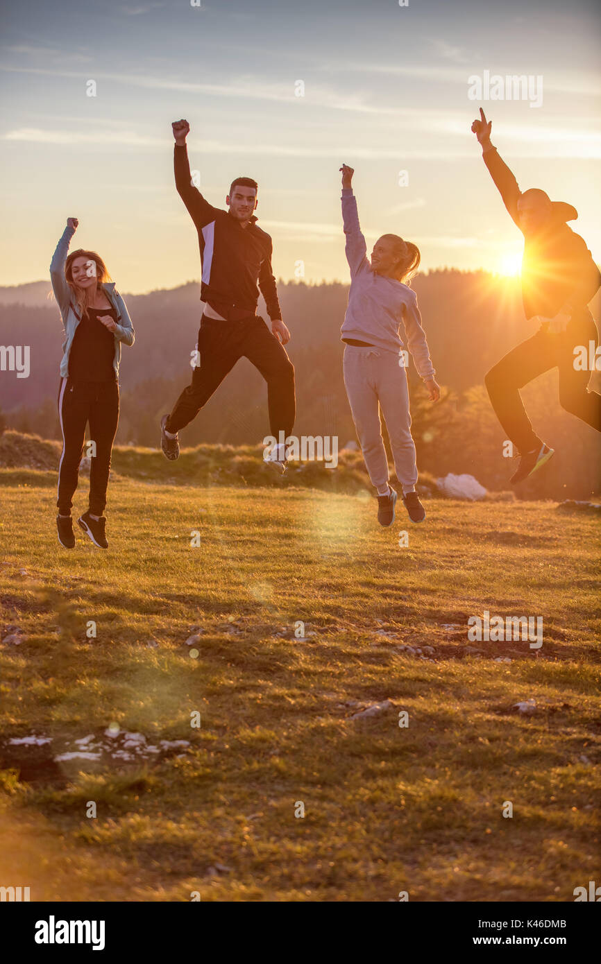 Group of friends running happily together in the grass and jumping ...