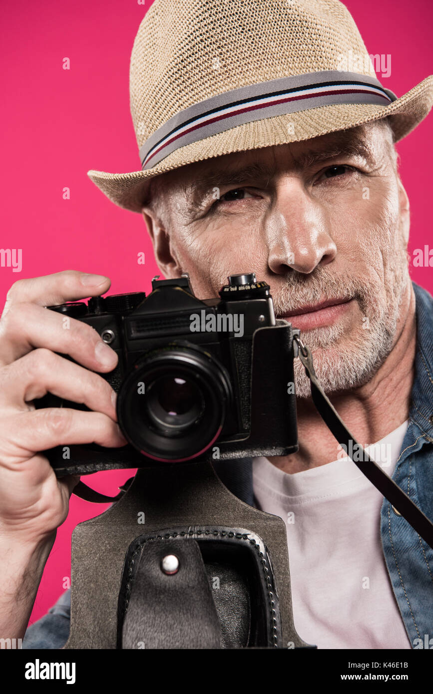 portrait of confident photographer holding photo camera and looking at ...