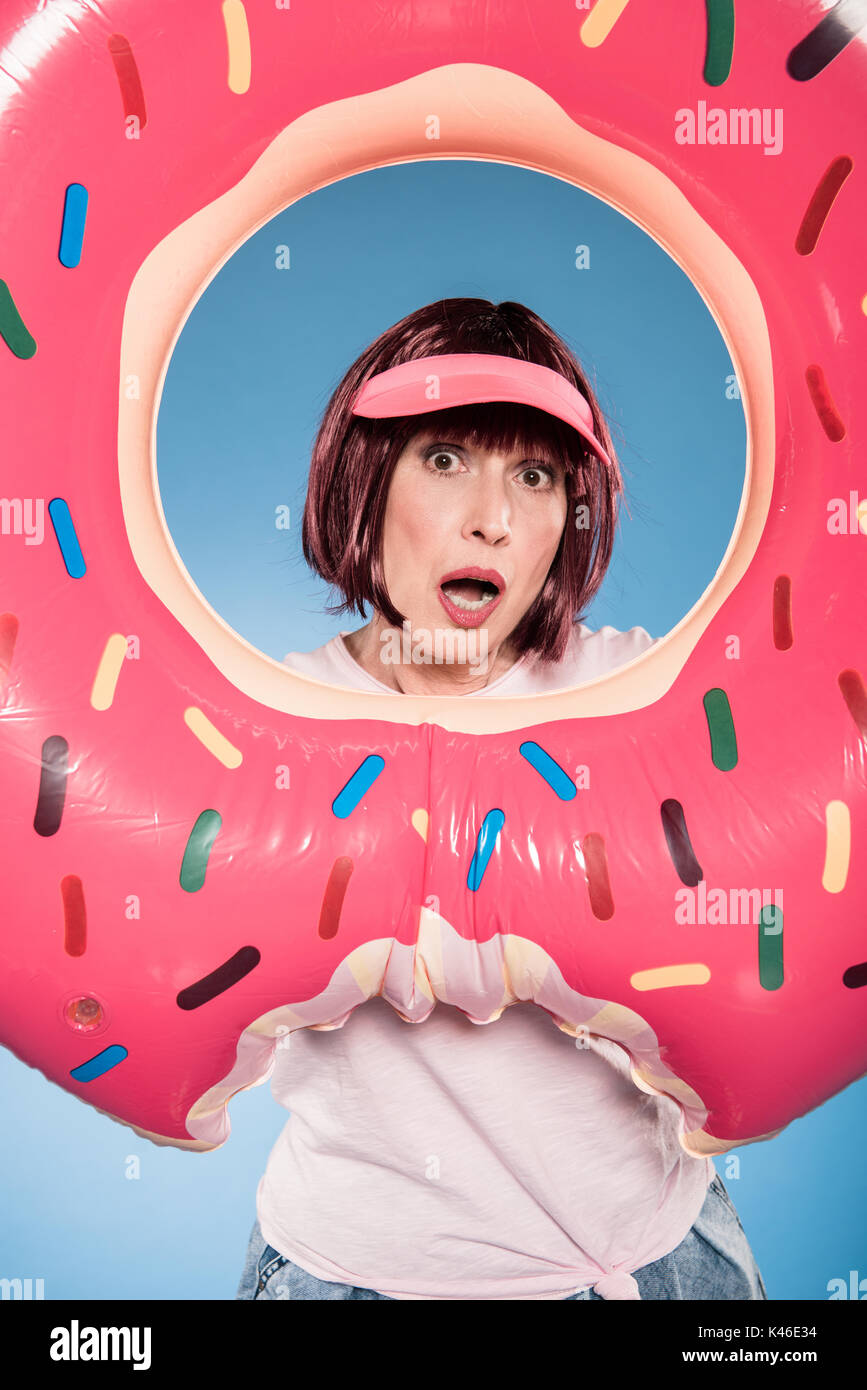 woman with facial expression holding float ring in form of doughnut ...