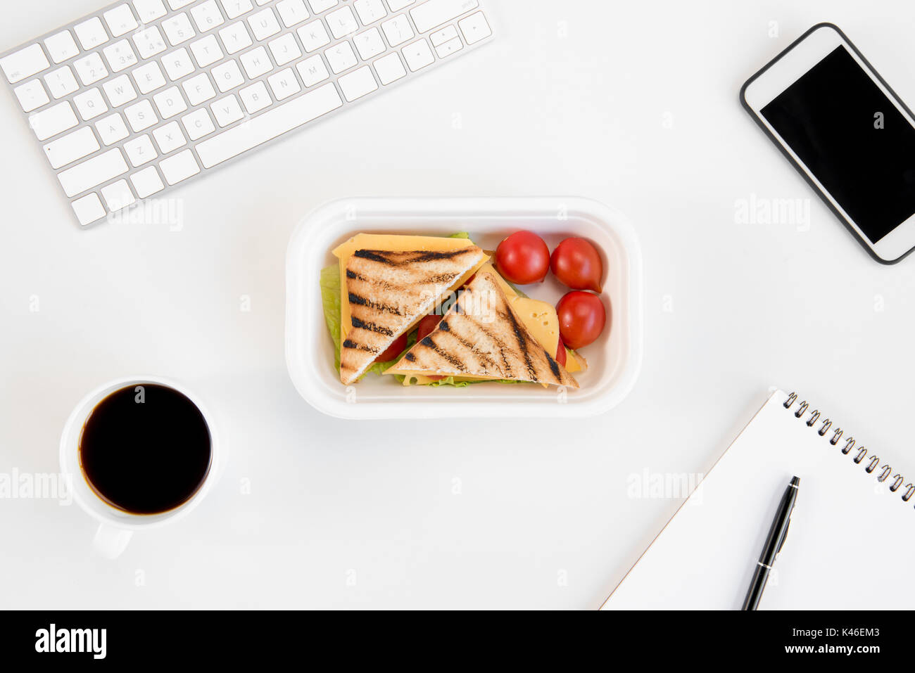 Top view of sandwiches with tomatoes in lunch box, notebook with pen ...