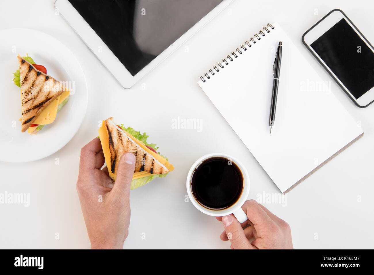Top view of person eating sandwiches and drinking coffee at workplace ...