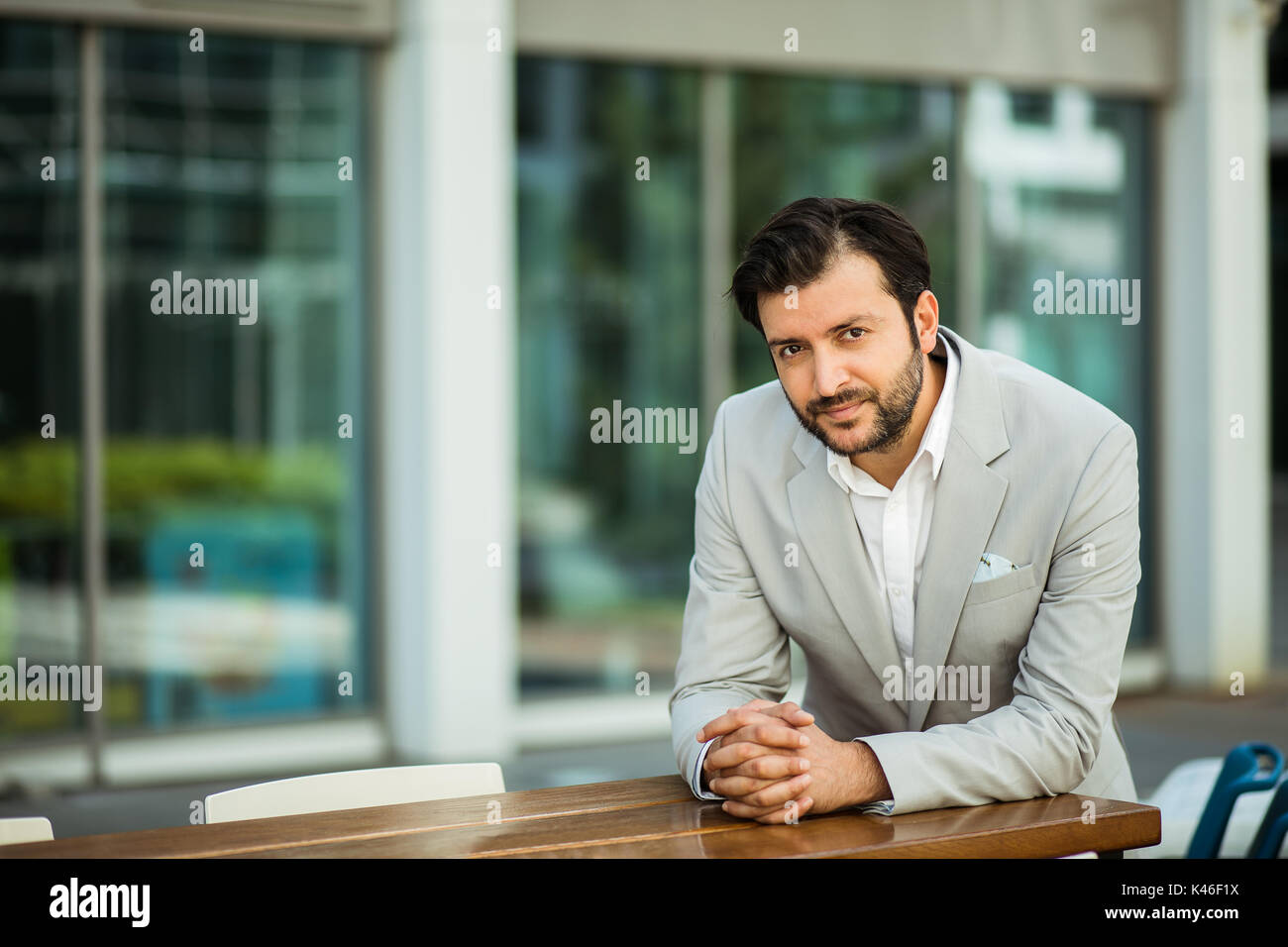 succesfull man in white shirt standing next to an office bulilding in a ...