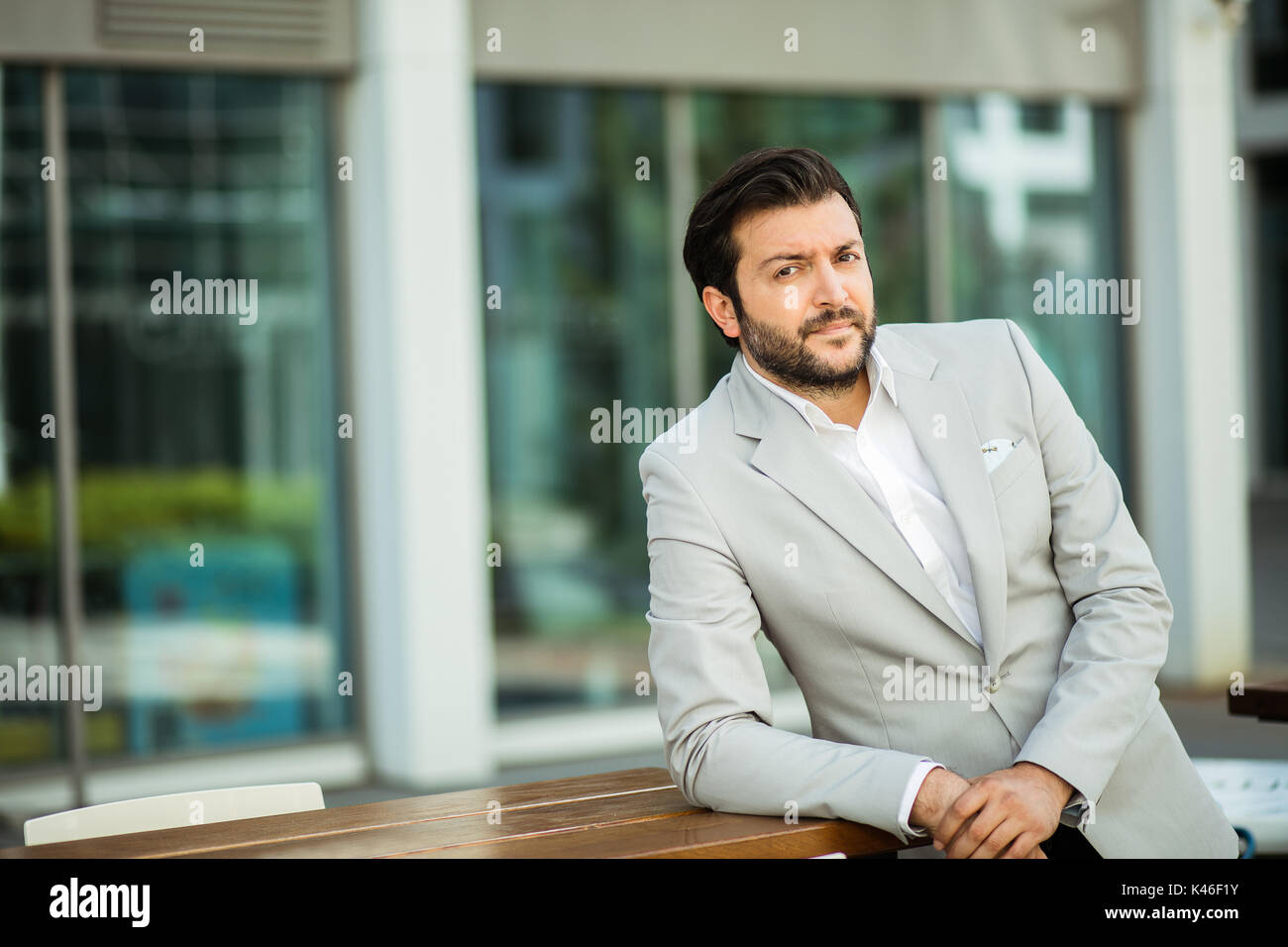 succesfull man in white shirt standing next to an office bulilding in a ...