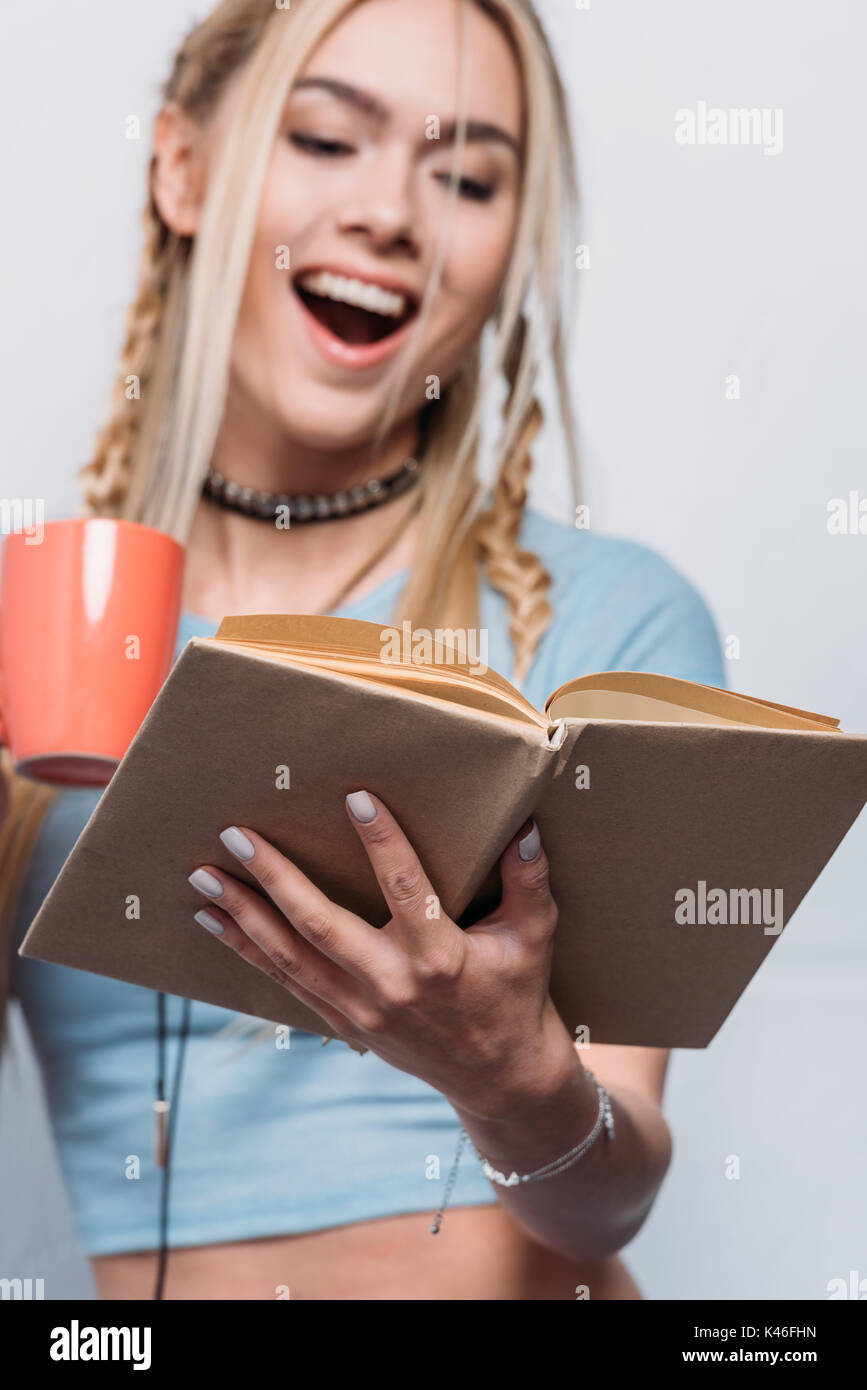 caucasian girl reading book and drinking coffee with facial expression ...
