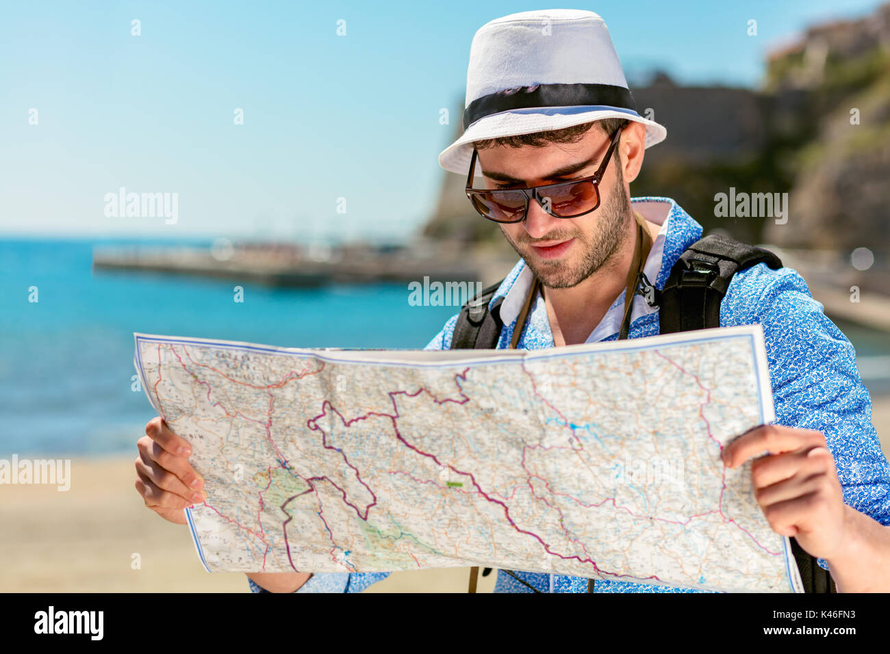Portrait of a smiling tourist with map and bag Stock Photo - Alamy