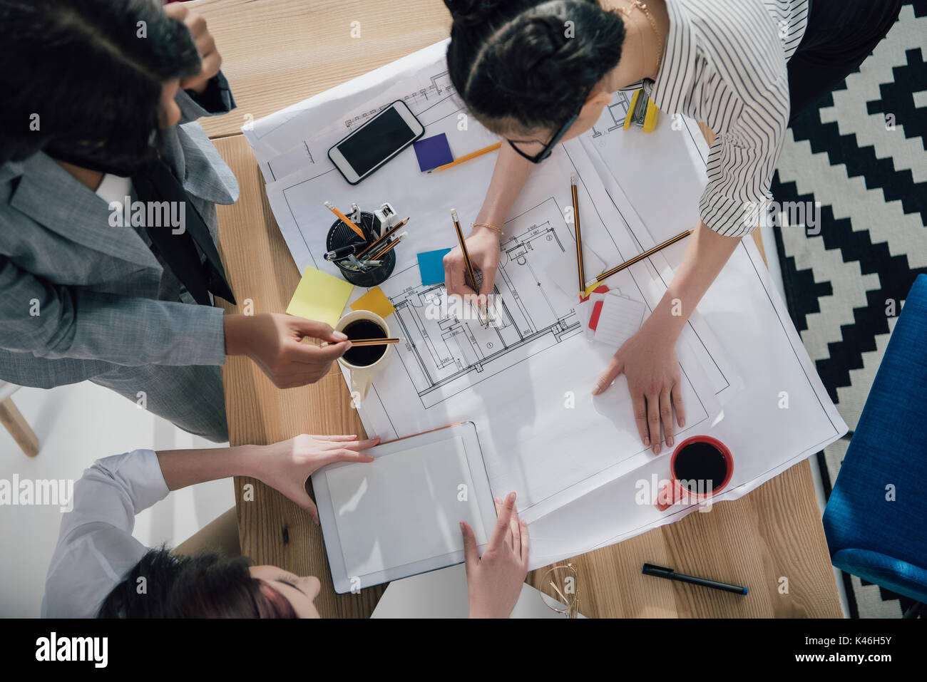 Overhead view of professional young architects working with blueprints ...