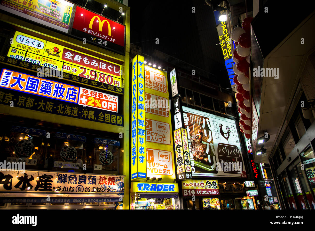 Shinjuku shops at night with its neon lights trying to draw in local ...