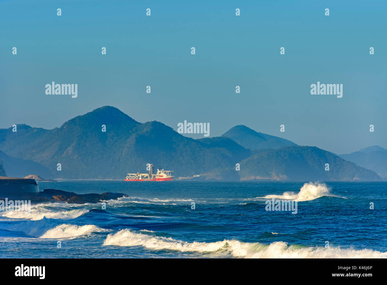 Small cargo ship sailing between islands, hills and forests of ...