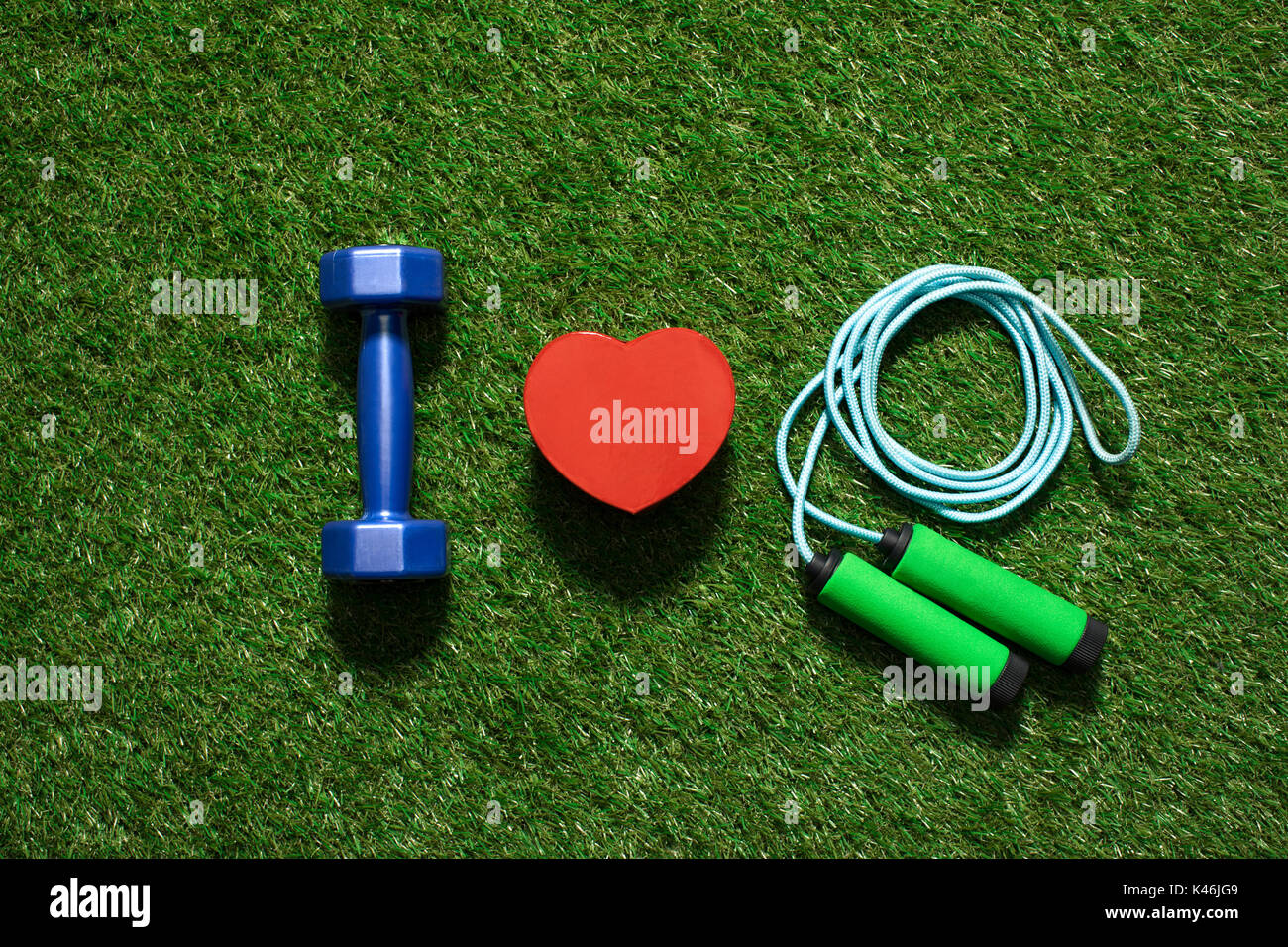 top view of colorful dumbbell with heart symbol and skipping rope on ...