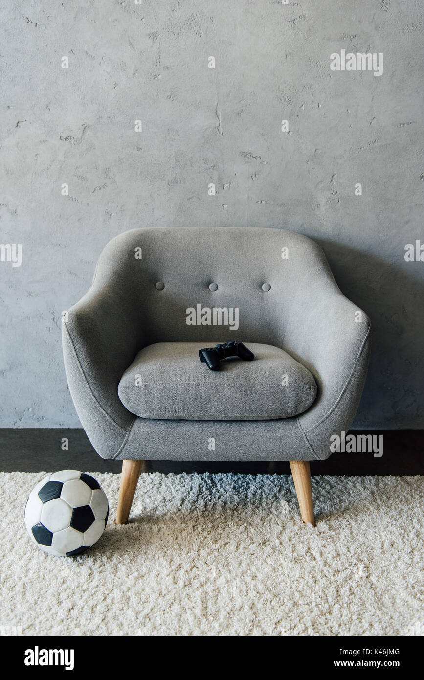 soccer ball near grey armchair with gamepad at empty room Stock Photo ...