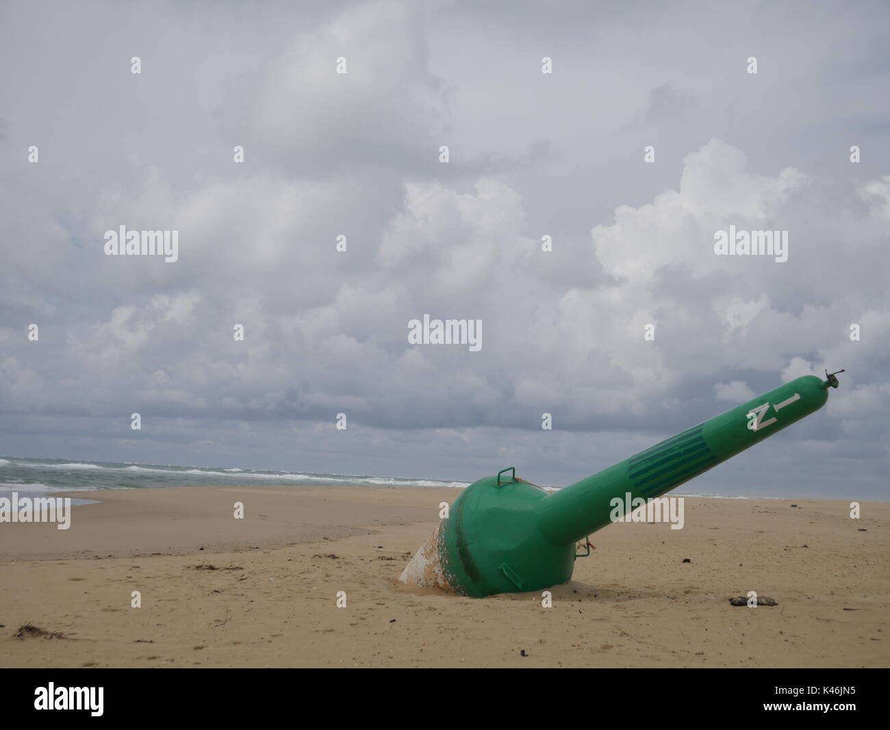 Green navigation buoy, washed up on an empty beach on a cold grey day ...