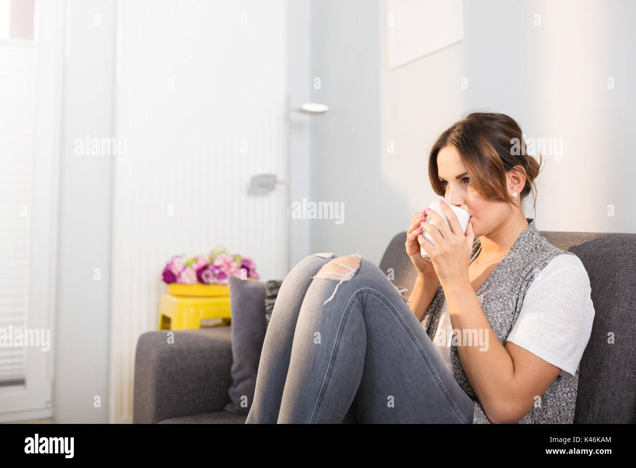 Portrait of young woman relaxing on couch drinking tea in silence Stock ...