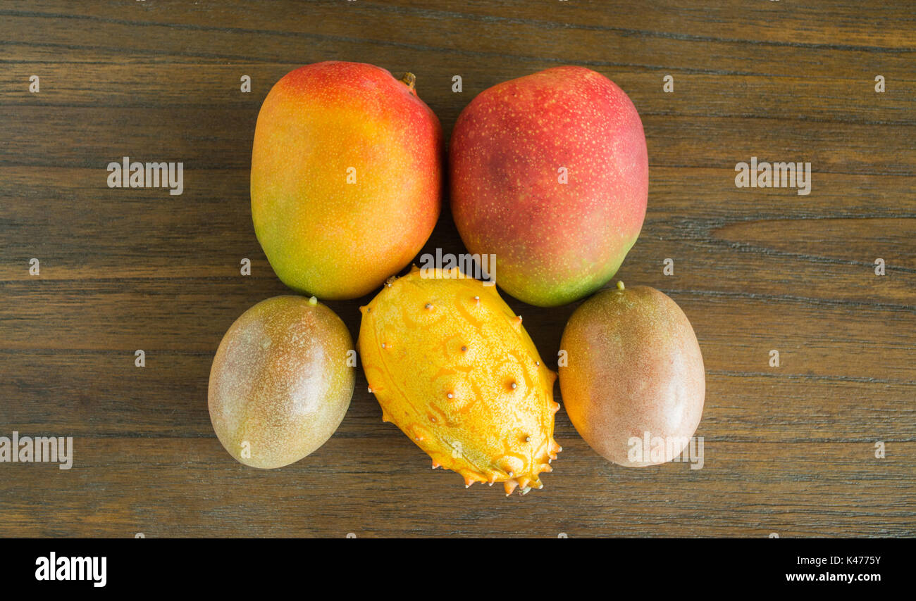 mangoes, passion fruit and melon isolated on a wooden table viewed from ...