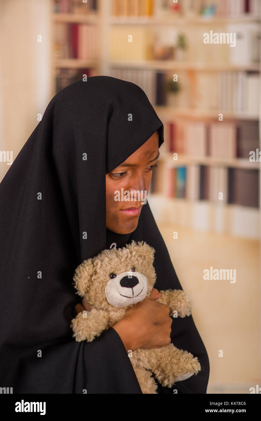 Portrait of a sad muslim girl wearing a hijab and holding her arms her ...