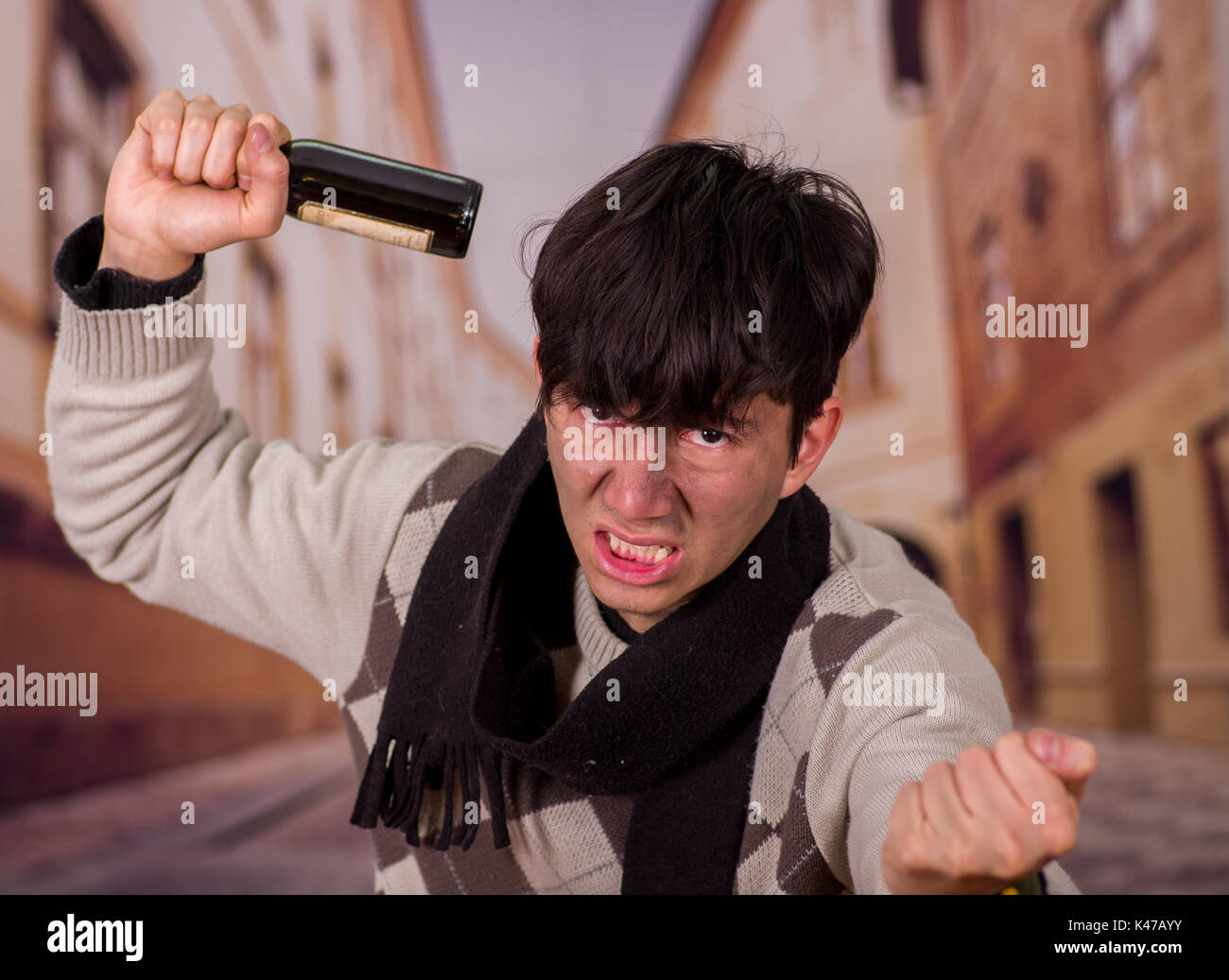 Portrait of an angry homeless young man in the streets, with a bottle ...
