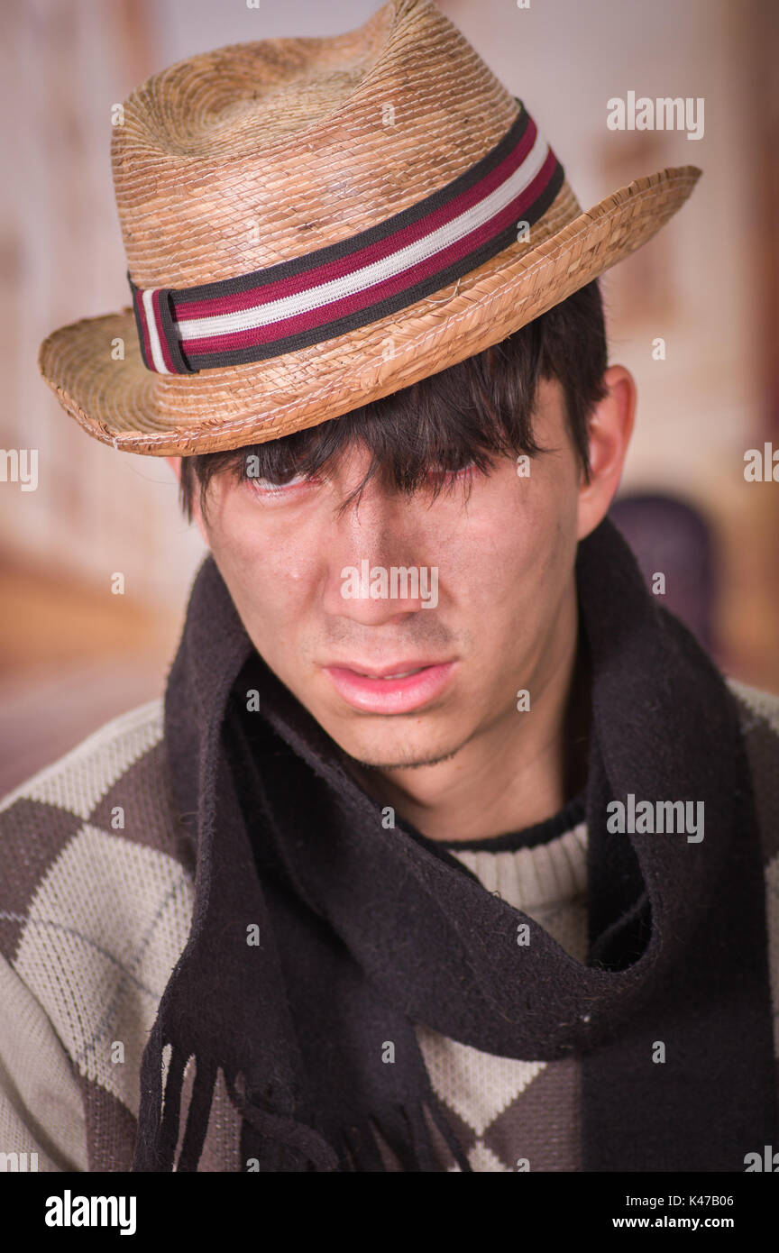 Close up of a sad homeless young man in the streets, wearing a hat and ...