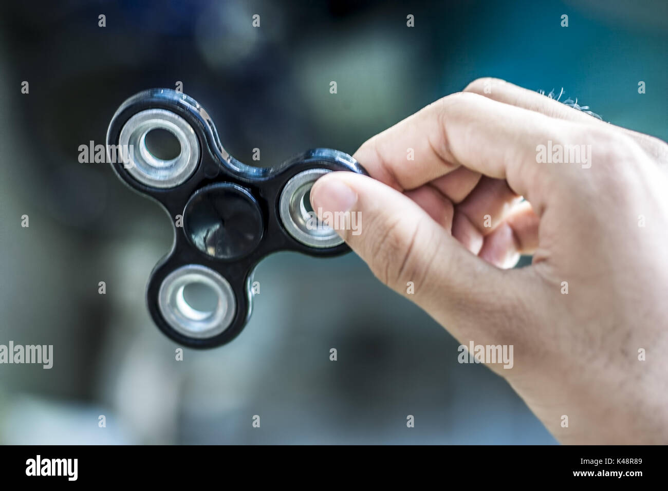 A hand holding a black fidget spinner Stock Photo - Alamy