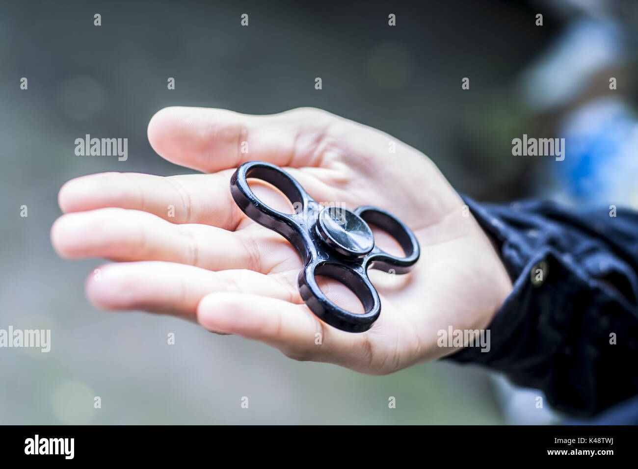 A hand holding a black fidget spinner Stock Photo - Alamy