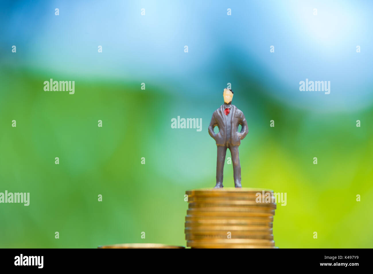 Miniature people, small figures businessmen stand on top of coins ...