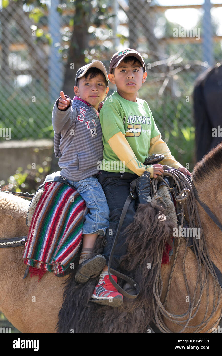 May 28, 2017 Sangolqui, Ecuador: two boys sitting in one saddle at a ...