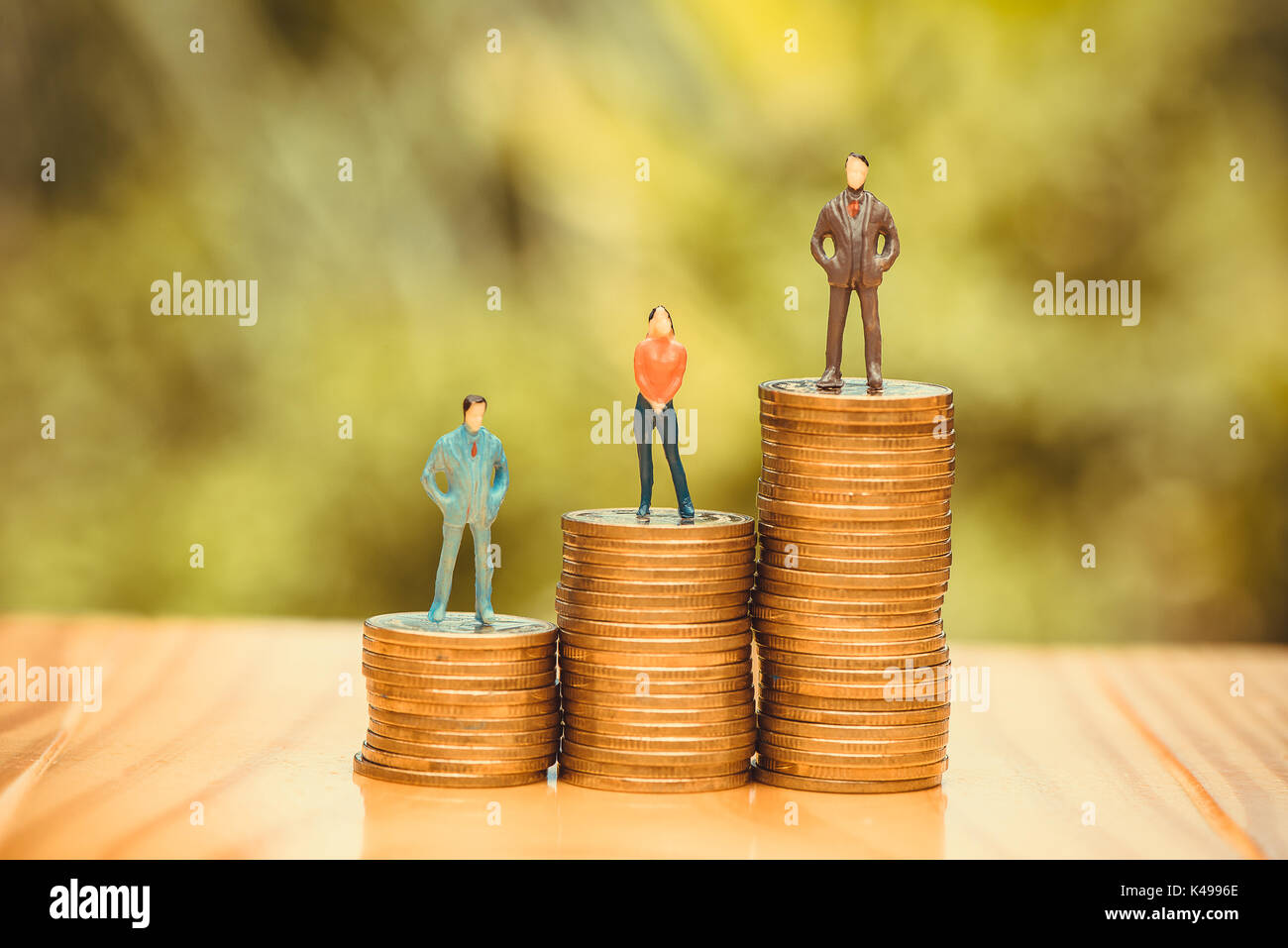 Miniature people, small figures businessmen and woman on top of coins ...