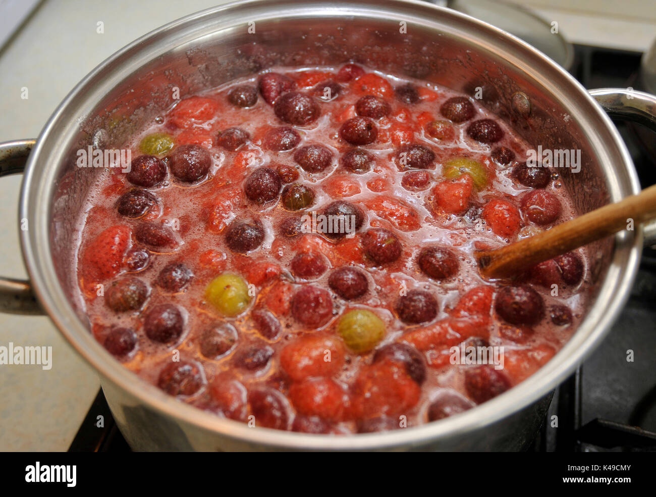 Early stage boiling red and white gooseberries, strawberries and sugar ...