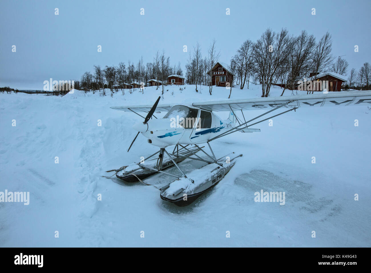 Hydroplane on the icy ground frames the wooden huts covered with snow ...