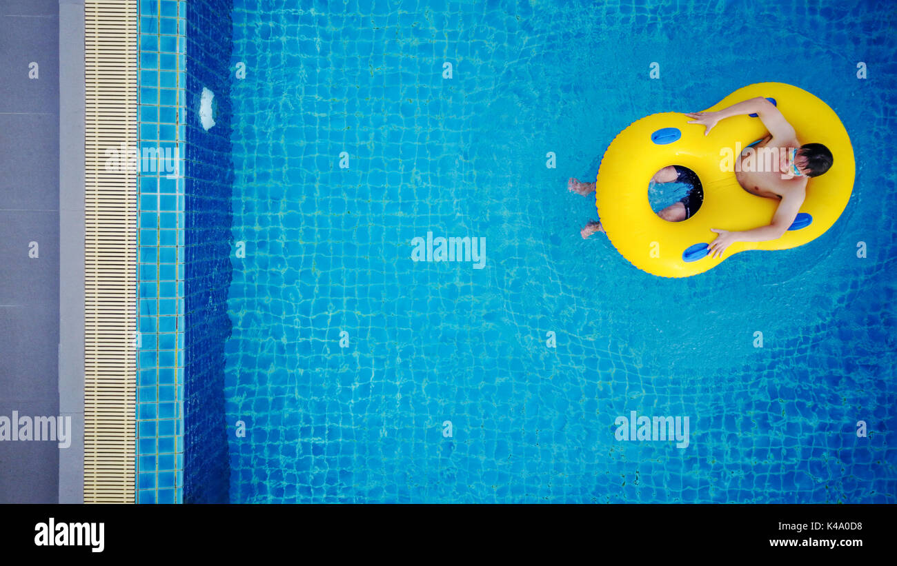 Aerial view, a man relax on yellow swim pool float, on swimming pool in ...
