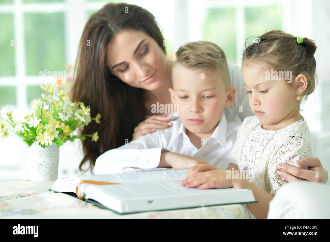 Mother and children reading book Stock Photo - Alamy