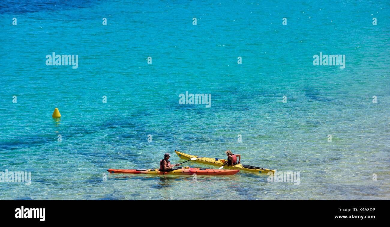 A man and a woman in kayaks in shallow sea water menorca minorca Stock ...