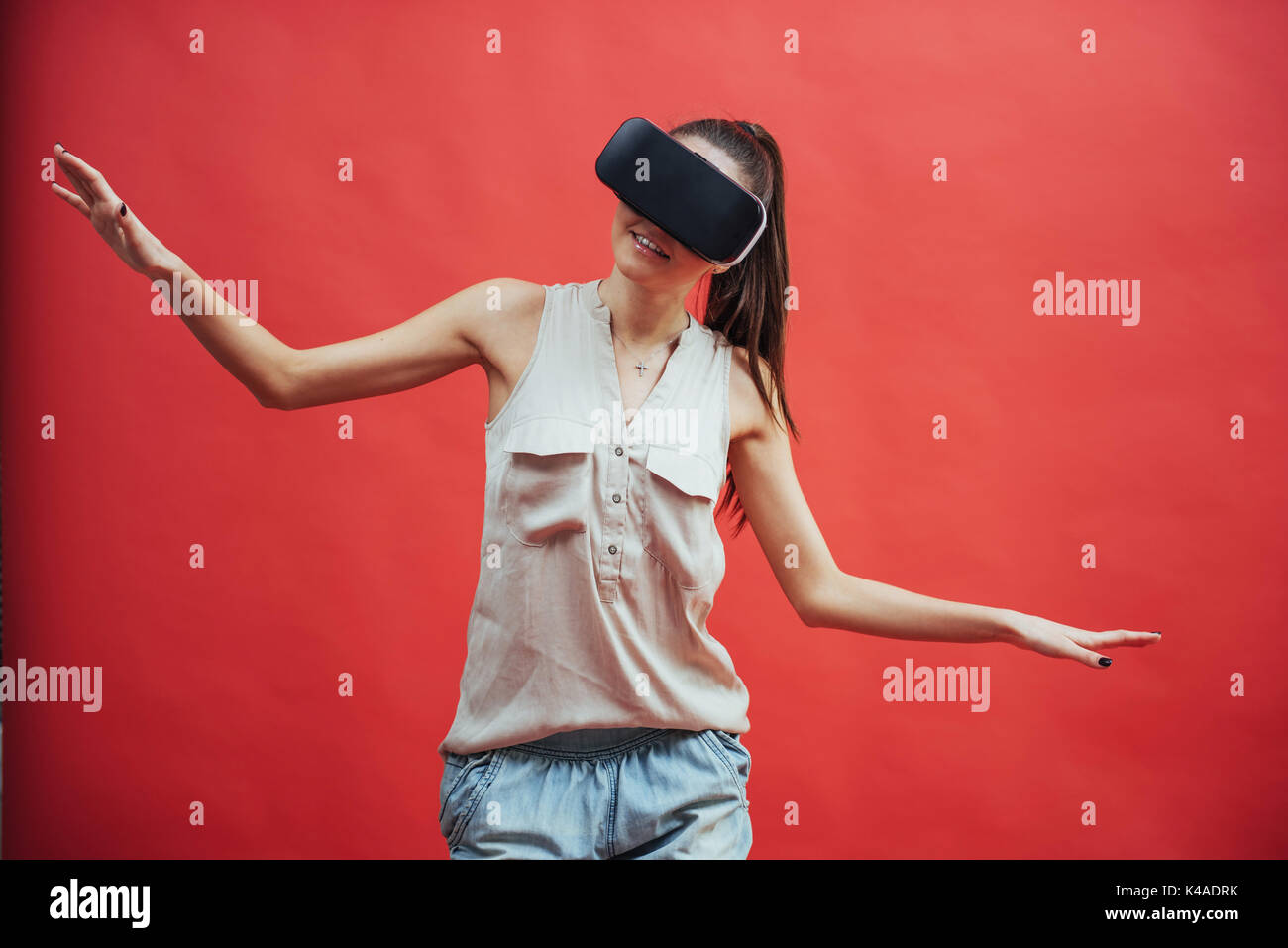 A young woman with a VR device on a red background in studio Stock ...
