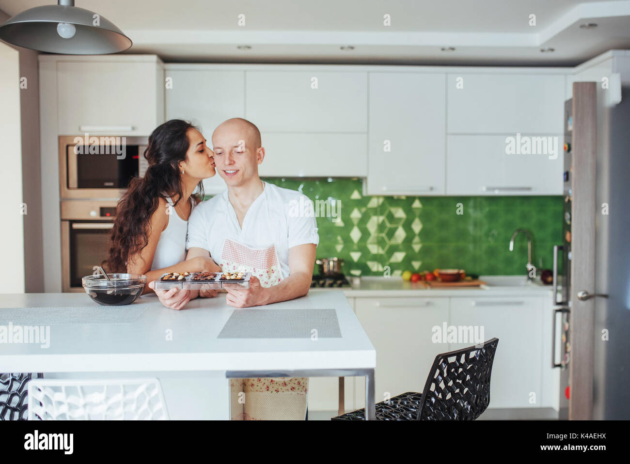 Beautiful young couple photographed smiling at the camera while cooking ...