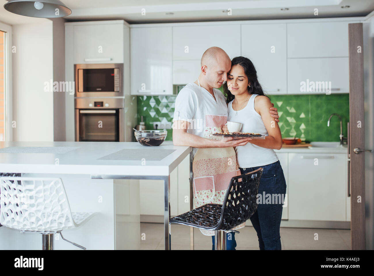 Beautiful young couple photographed smiling at the camera while cooking ...