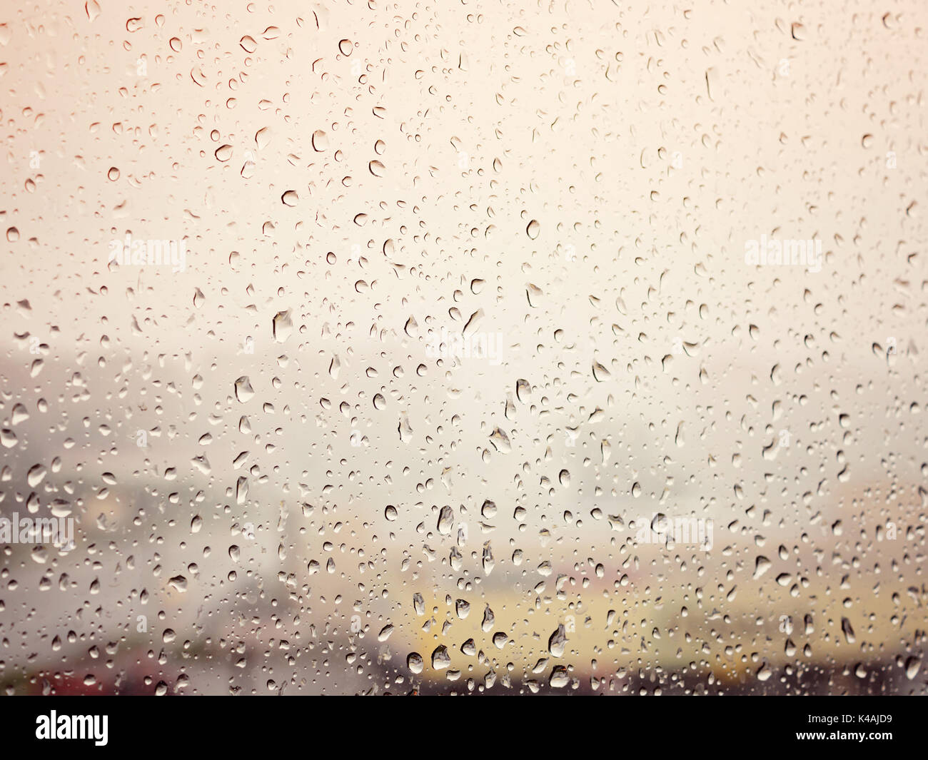 Rain in city, water drops on wet window glass, sunset. Blured background Stock Photo - Alamy