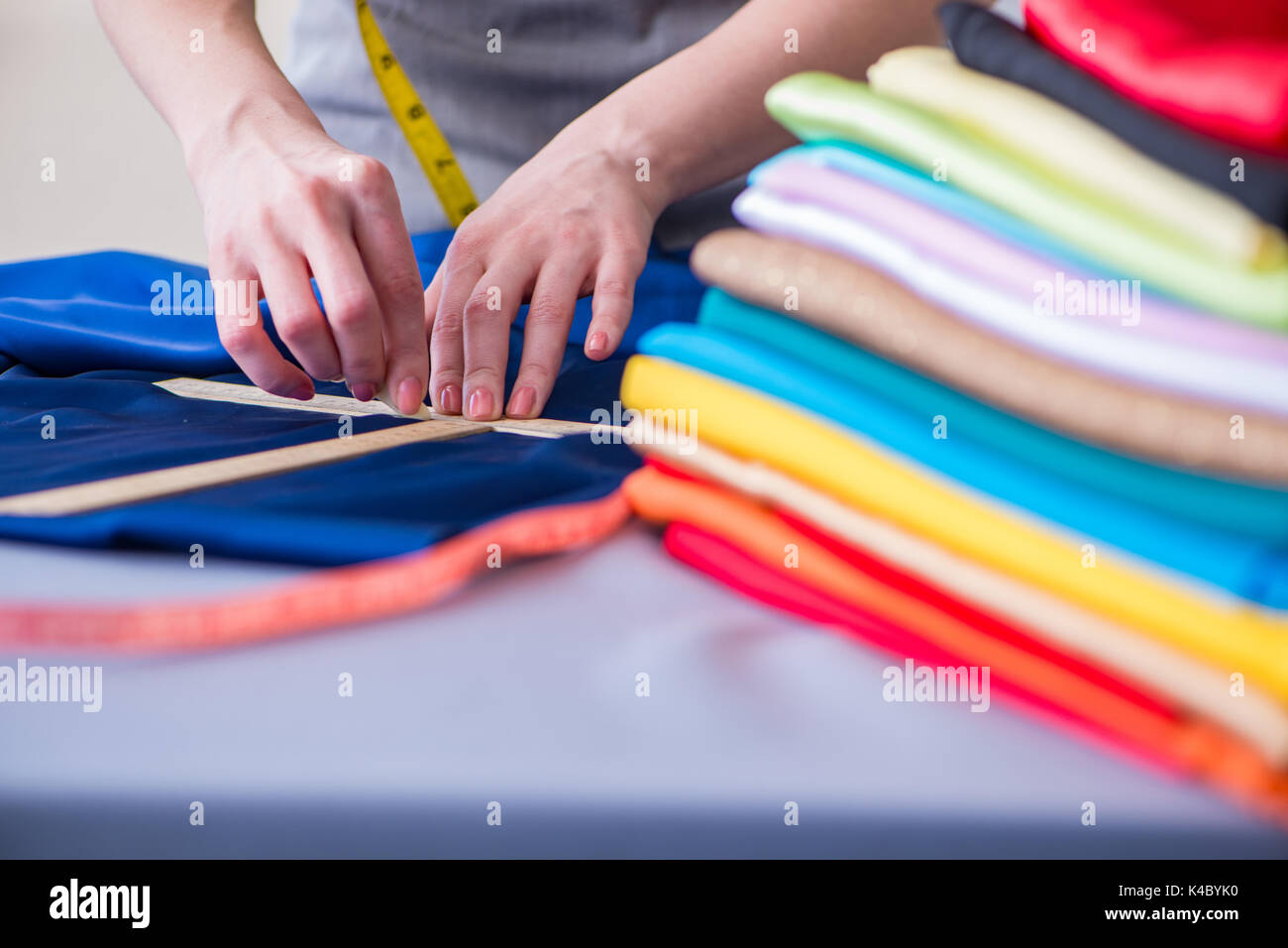 Woman tailor working on a clothing sewing stitching measuring fabric ...