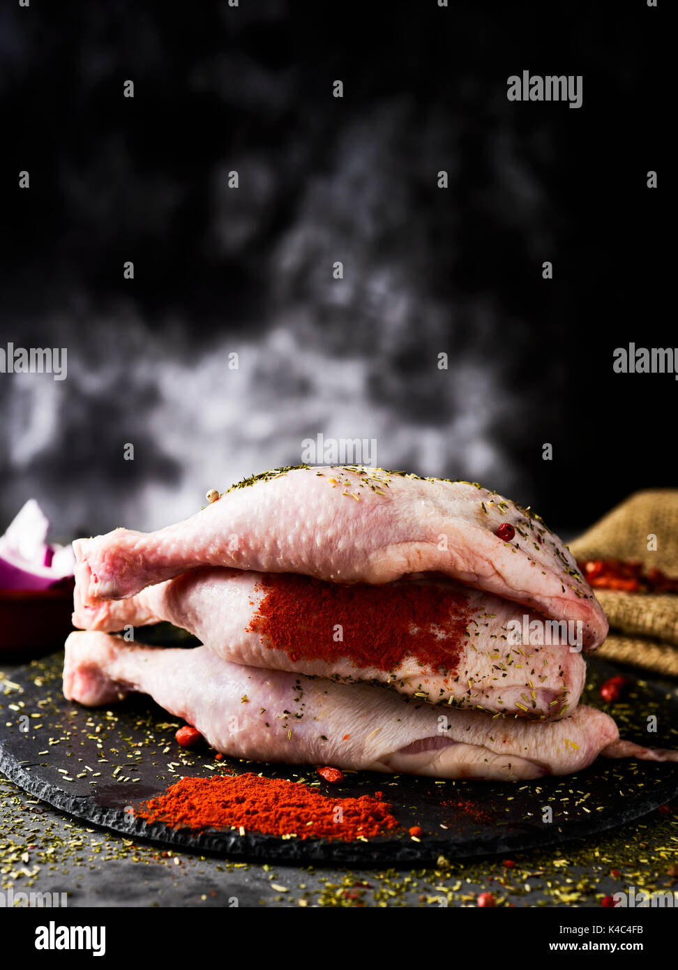 closeup of some raw chicken legs on a slate plate, placed on a rustic ...
