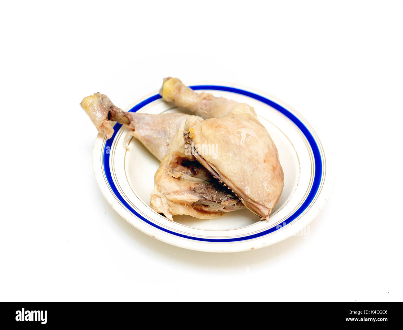 Cooked chicken quarter in a plate laid on the top of a white table ...